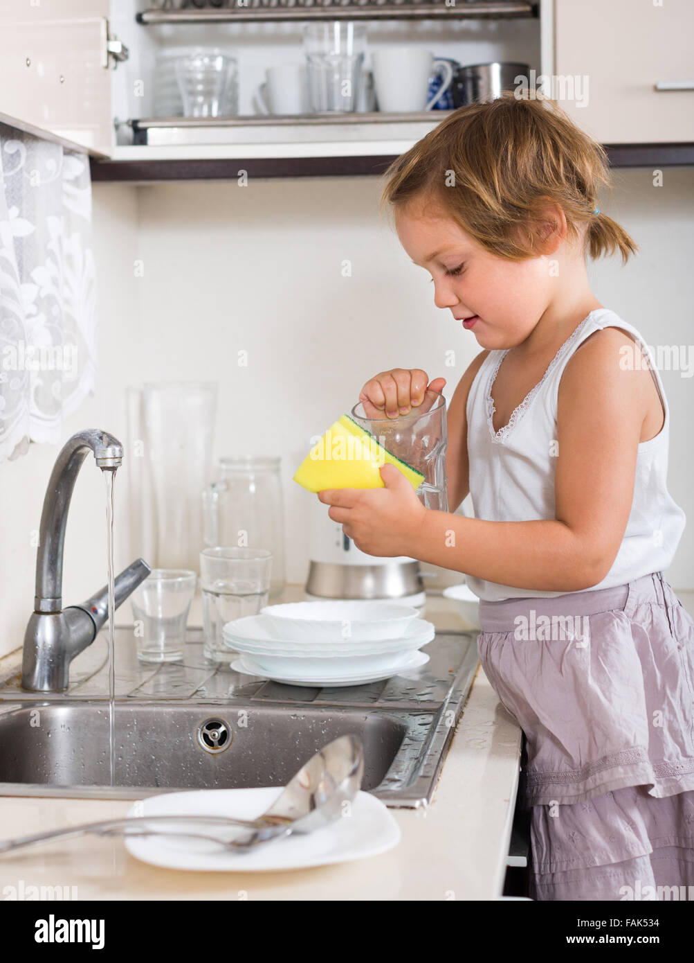 Joyful cute little girl washing dishes at home kitchen Stock Photo - Alamy