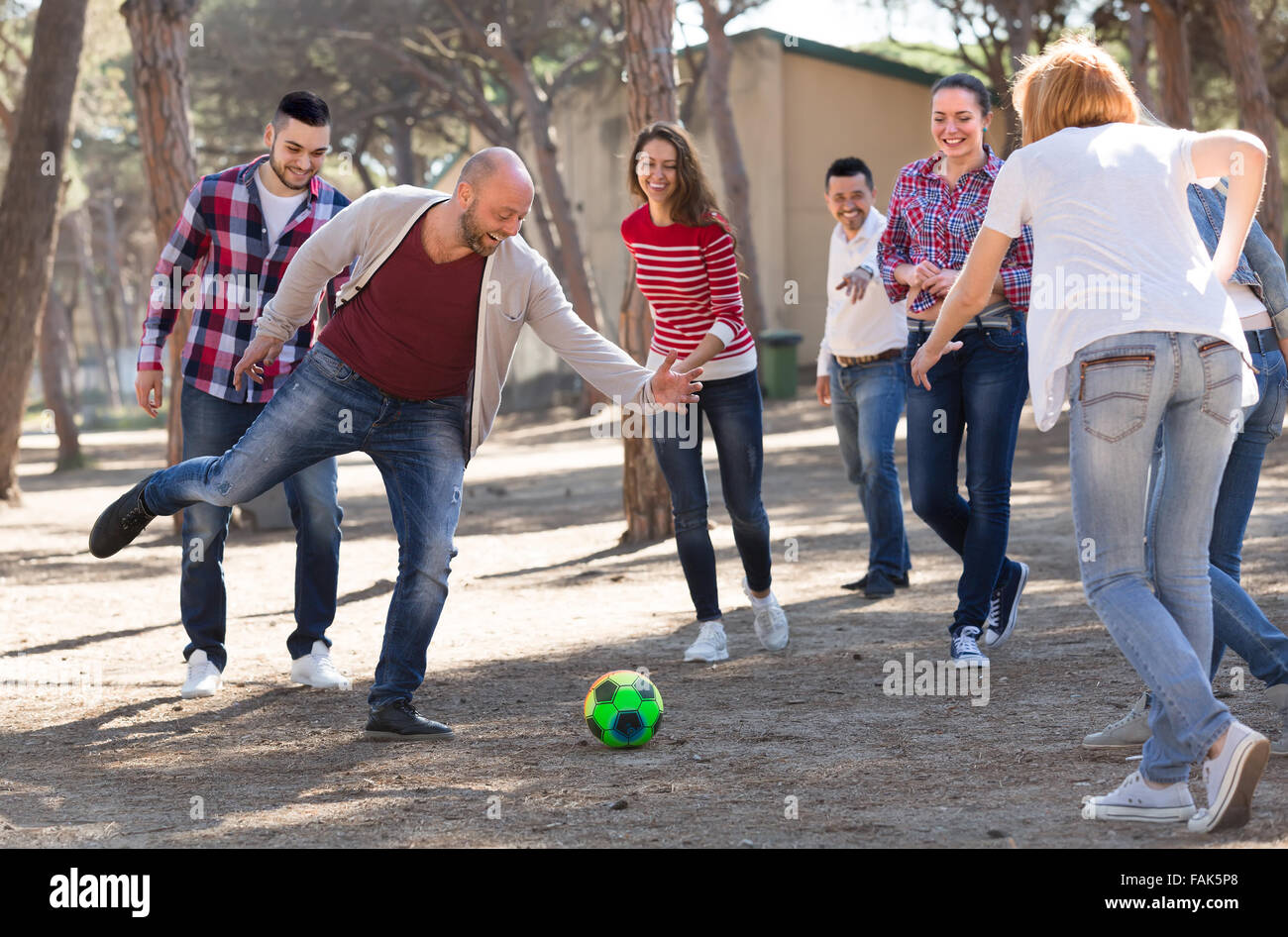 Group of friends playing football at picnic lunch. Selective focus ...