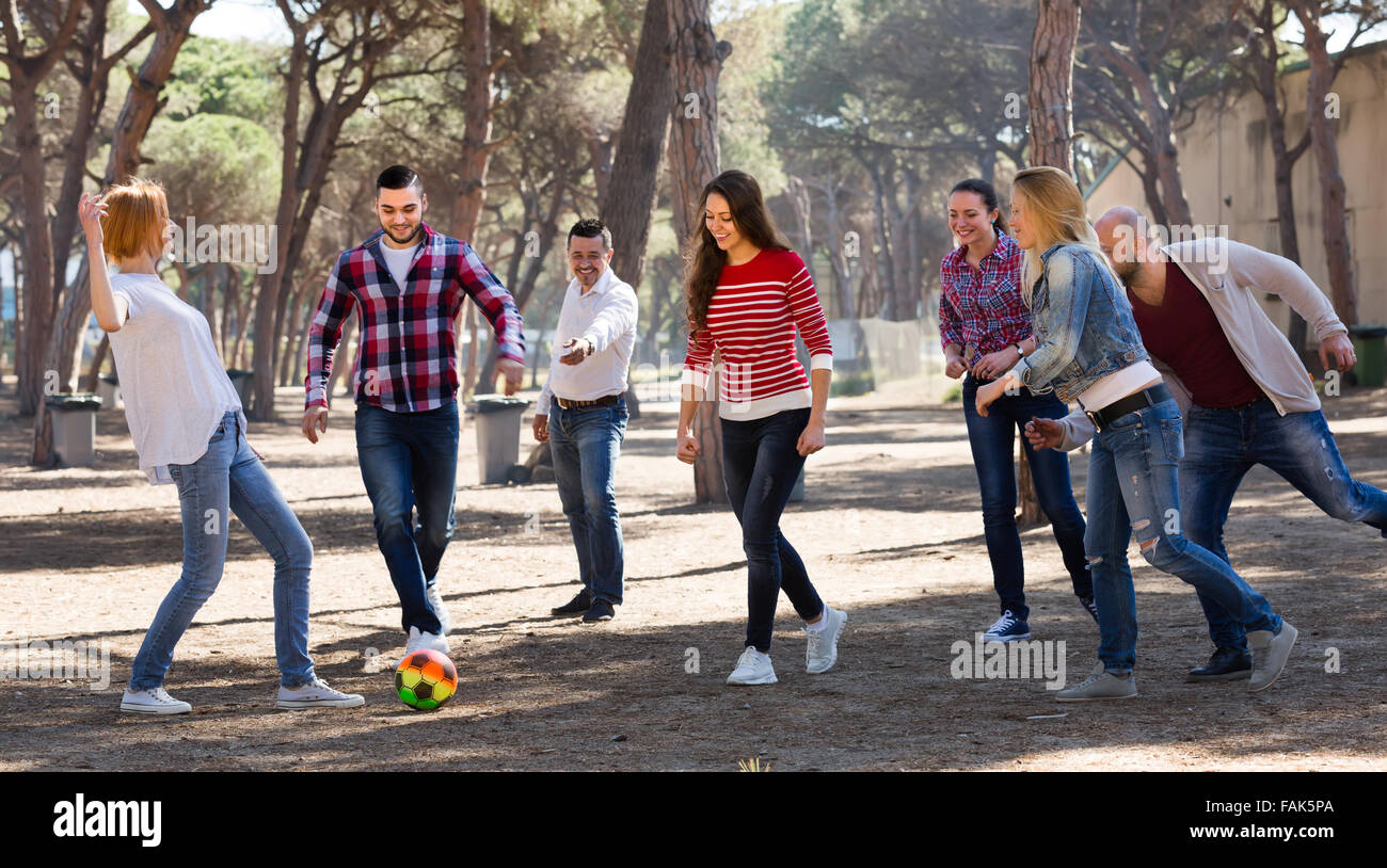 Group of active friends playing football at picnic lunch. Selective ...