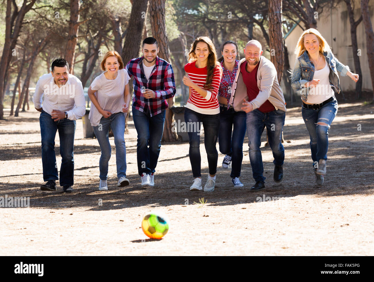 Positive adults chasing ball outdoors at sunny day Stock Photo - Alamy