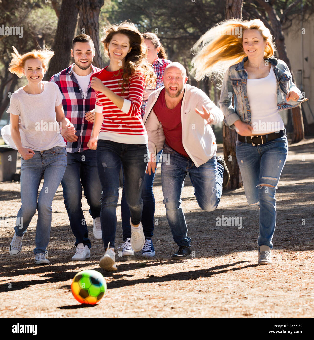 Several happy friends running with a ball and laughing Stock Photo - Alamy