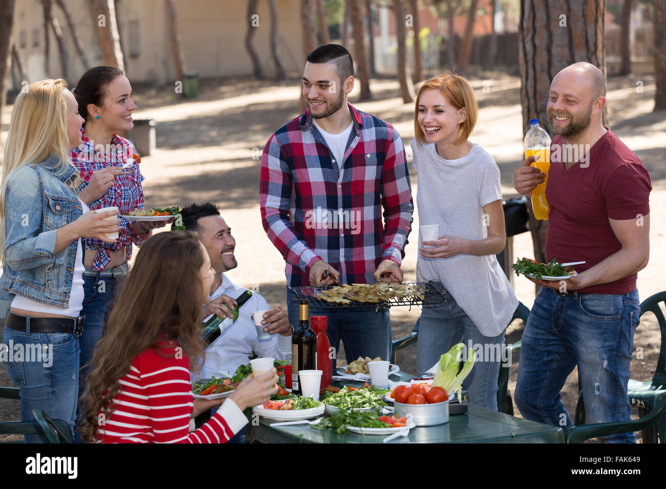 Happy friends making grill at summer corporate party outdoors ...
