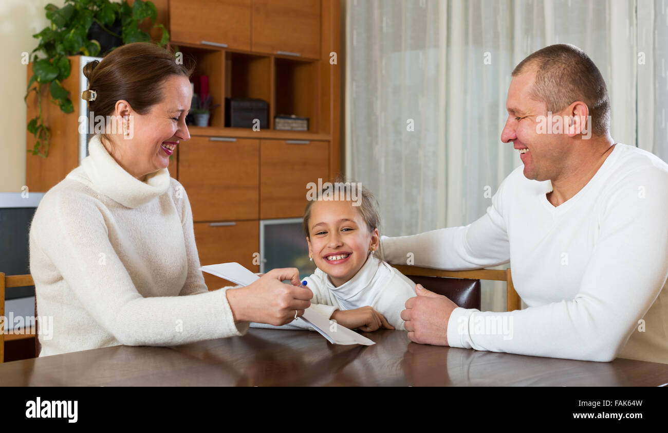 Happy parents and child with documents at table in the living room ...