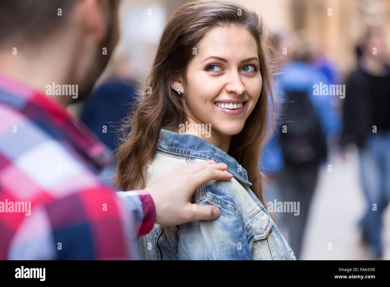 Young man stops a beautiful happy woman on a street to pick her up ...
