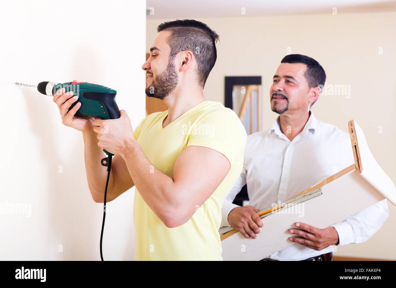 Two happy men doing maintenance work at home. Focus on the left man ...