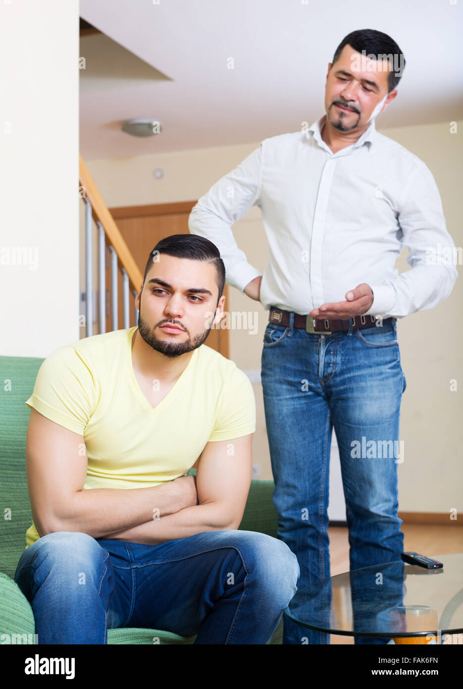 Two serious male adults arguing about something indoors after quarrel ...