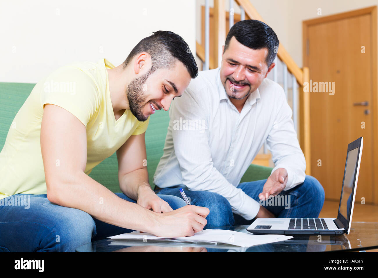 Senior father helping happy young son to fill application form Stock ...