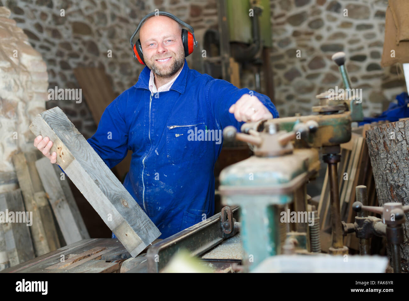 Positive smiling professional worker working on a machine at wood ...