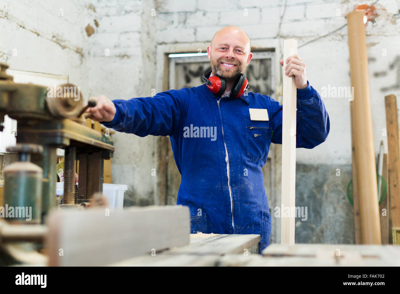 Positive adult professional woodworker on lathe at musical instrument ...