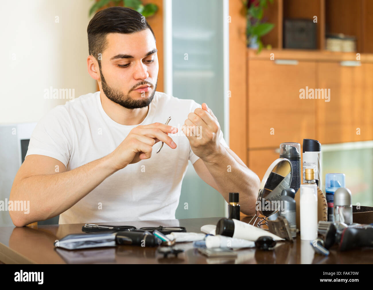 Young guy cutting nails with cuticle scissors Stock Photo - Alamy