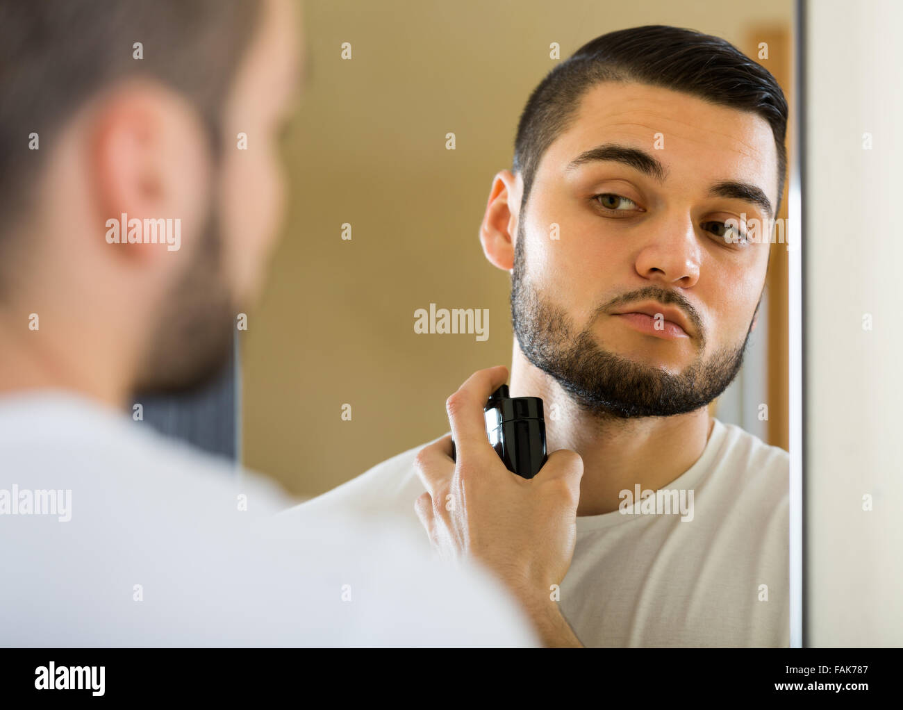 Young handsome guy using perfume in front of mirror Stock Photo - Alamy