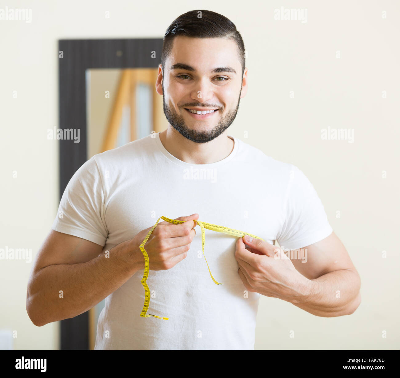 Handsome european man measuring his bicep and body Stock Photo - Alamy