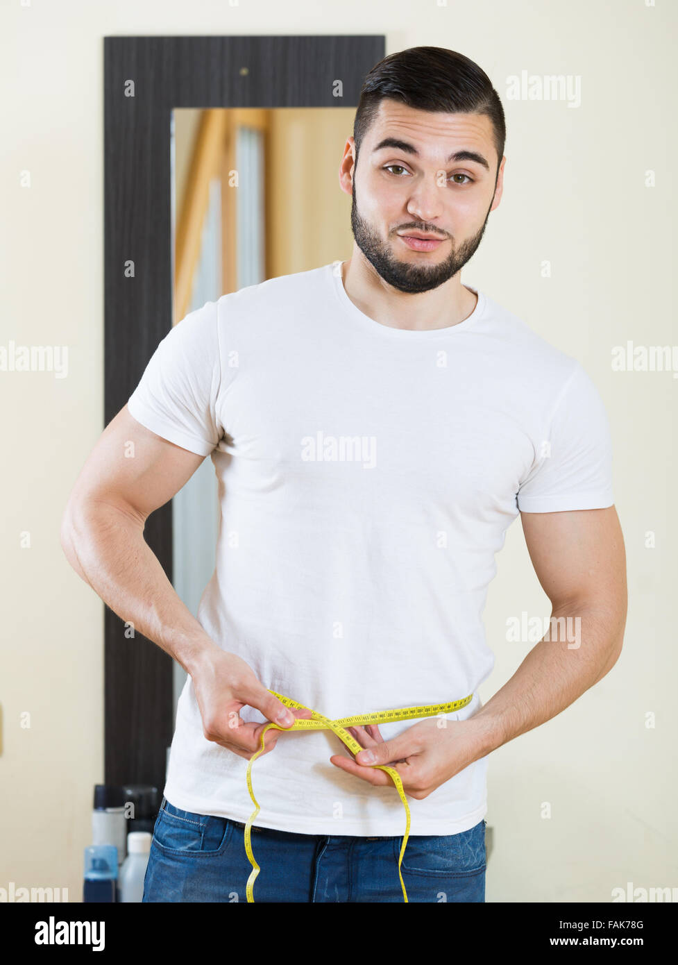Handsome man measuring his bicep and body Stock Photo - Alamy
