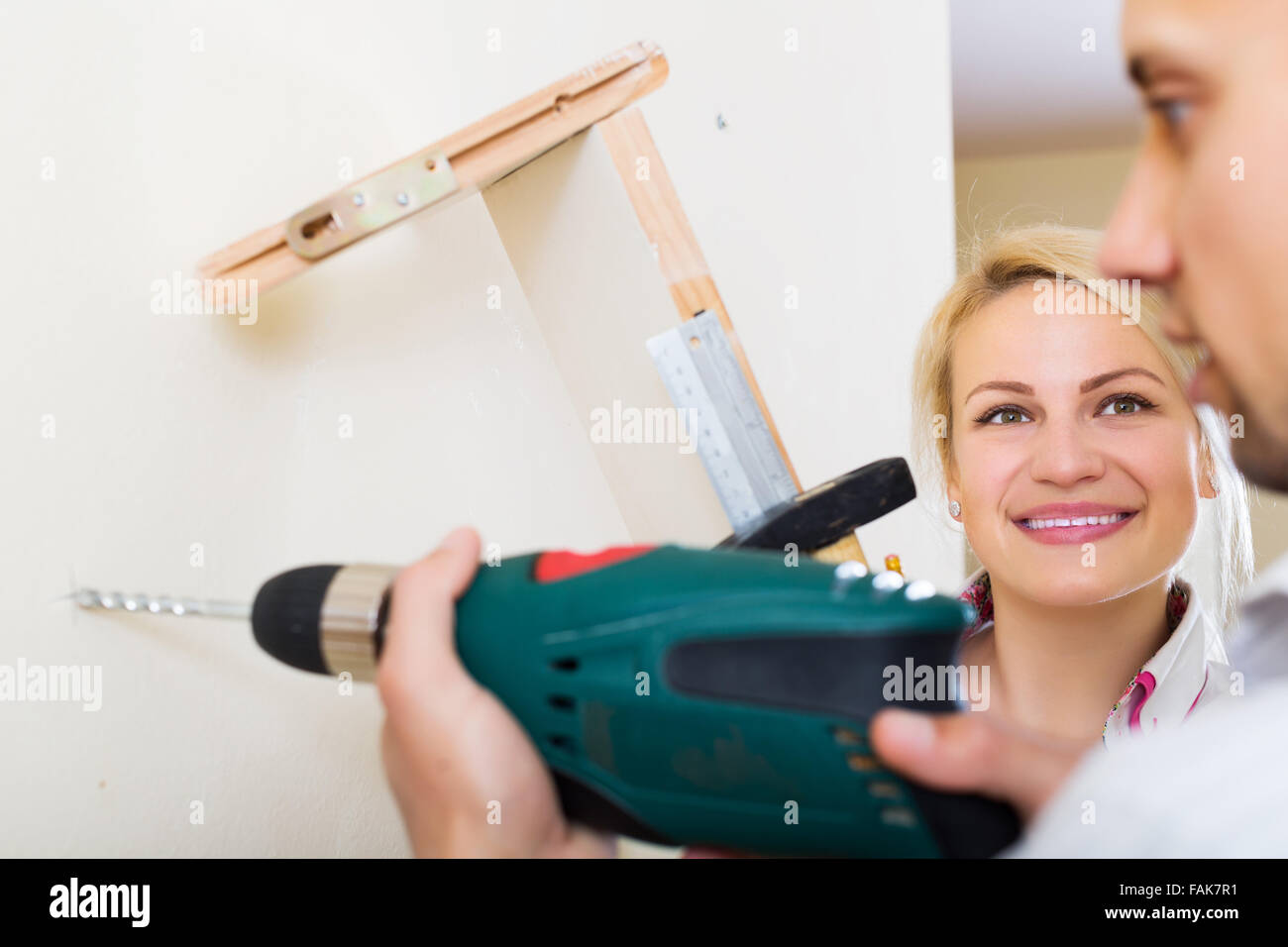 Man and happy young woman choosing place for shelf at home Stock Photo ...