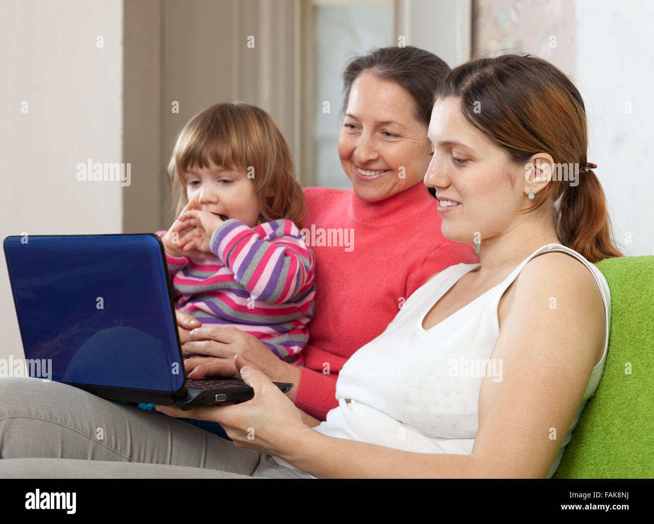 Family of three generations with laptop on sofa Stock Photo - Alamy