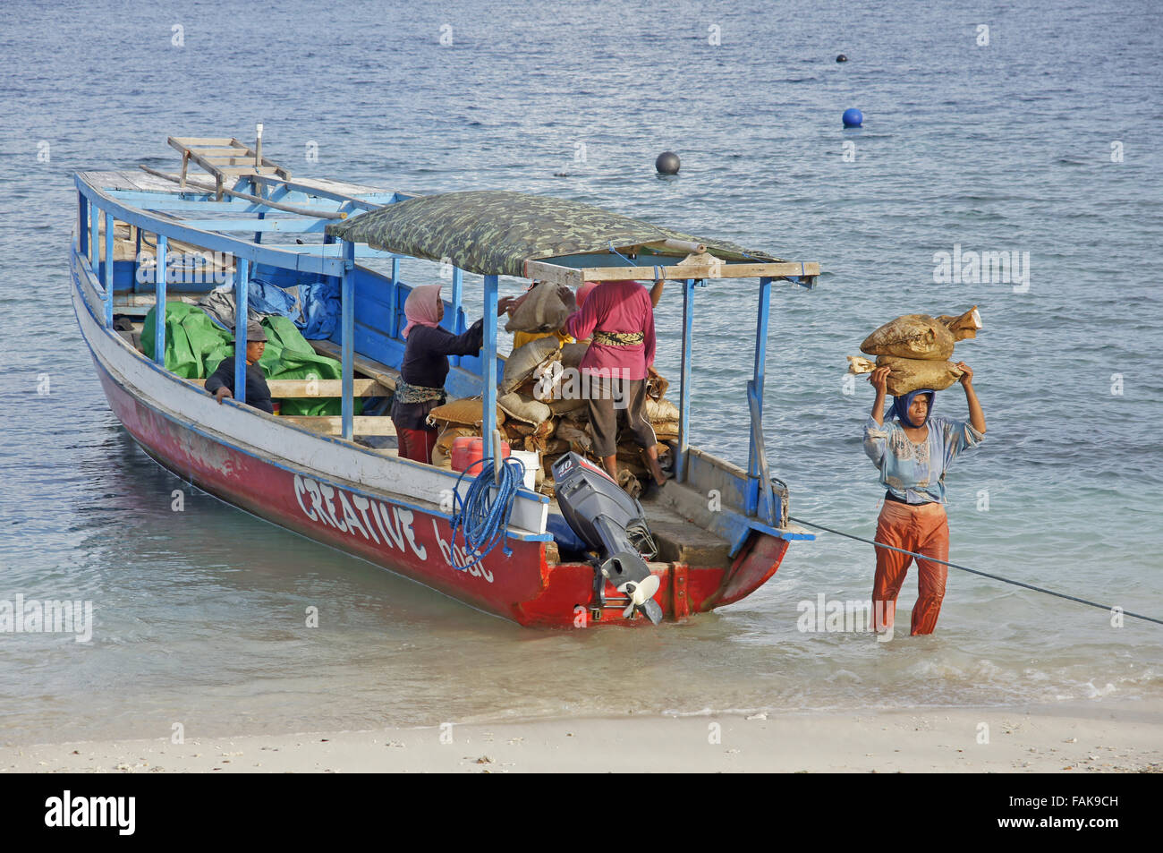 Female porters carry heavy goods off of a boat. Gili Islands, Indonesia ...