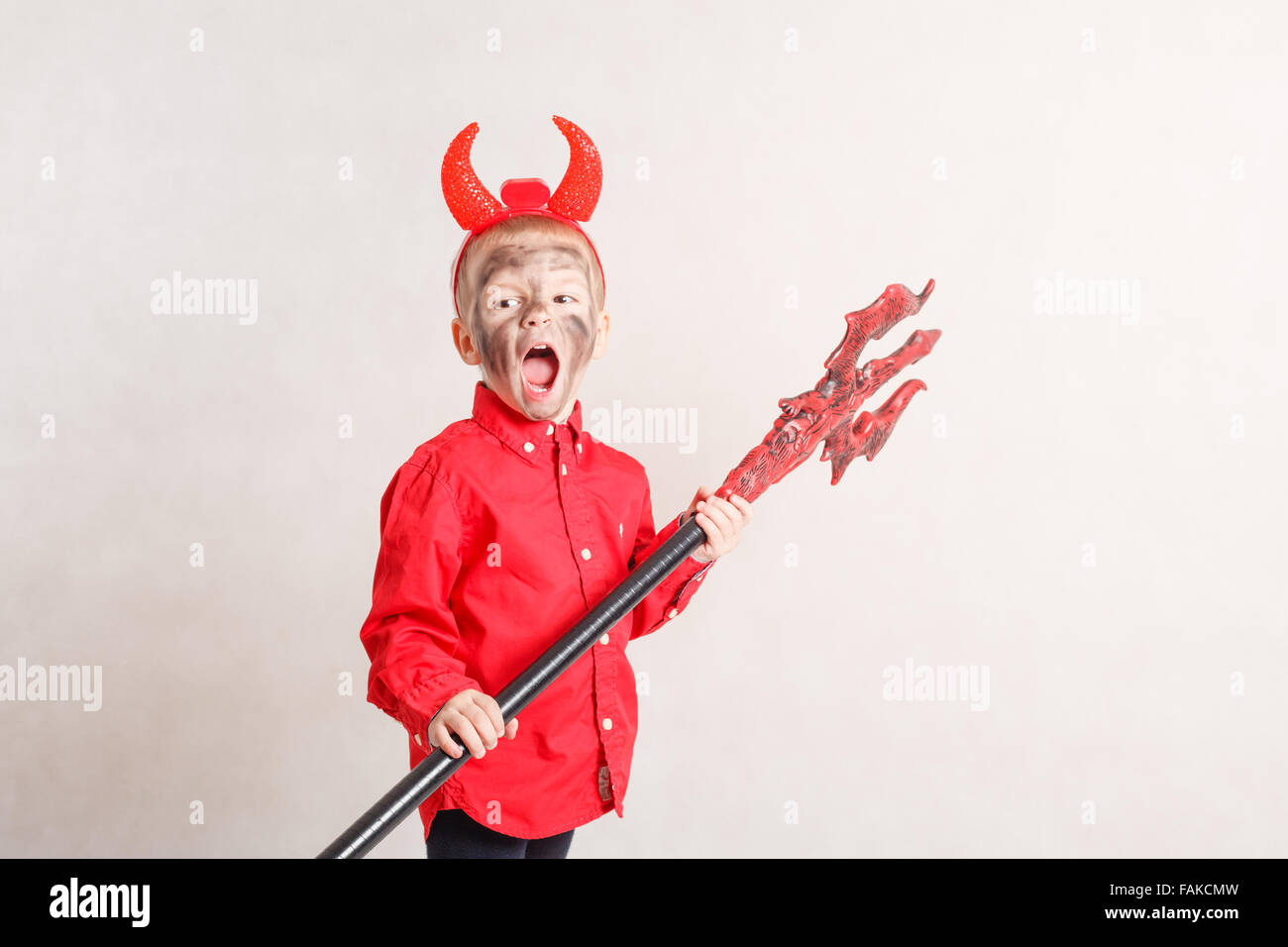 Little boy with trident in a devil costume (on white background Stock ...