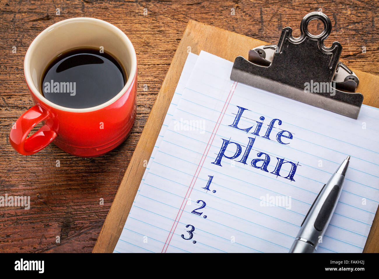 Life plan concept -a list on clipboard against grunge wood desk with a ...