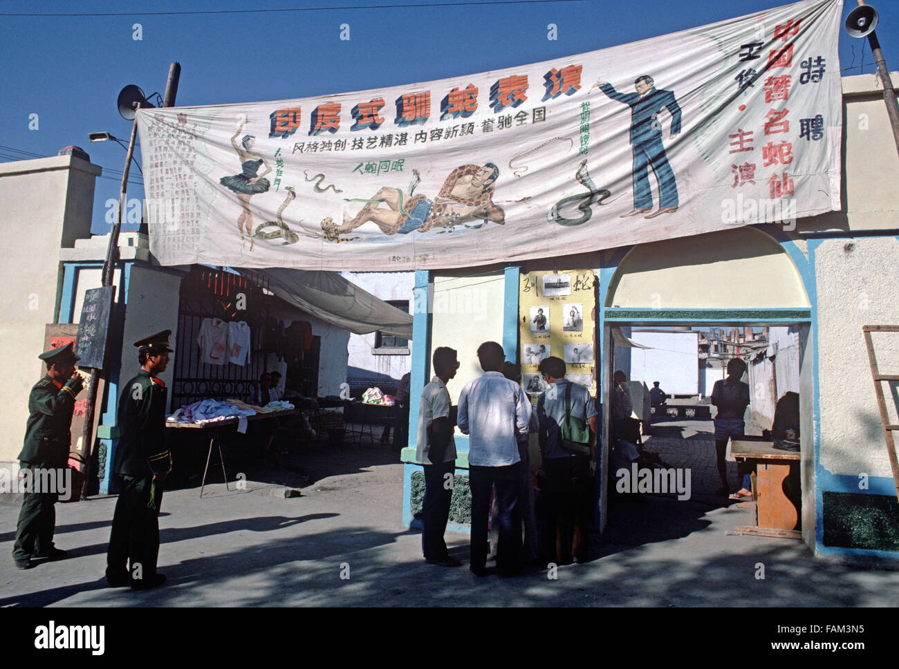 Chinese policemen standing outside market with snake charmers poster ...