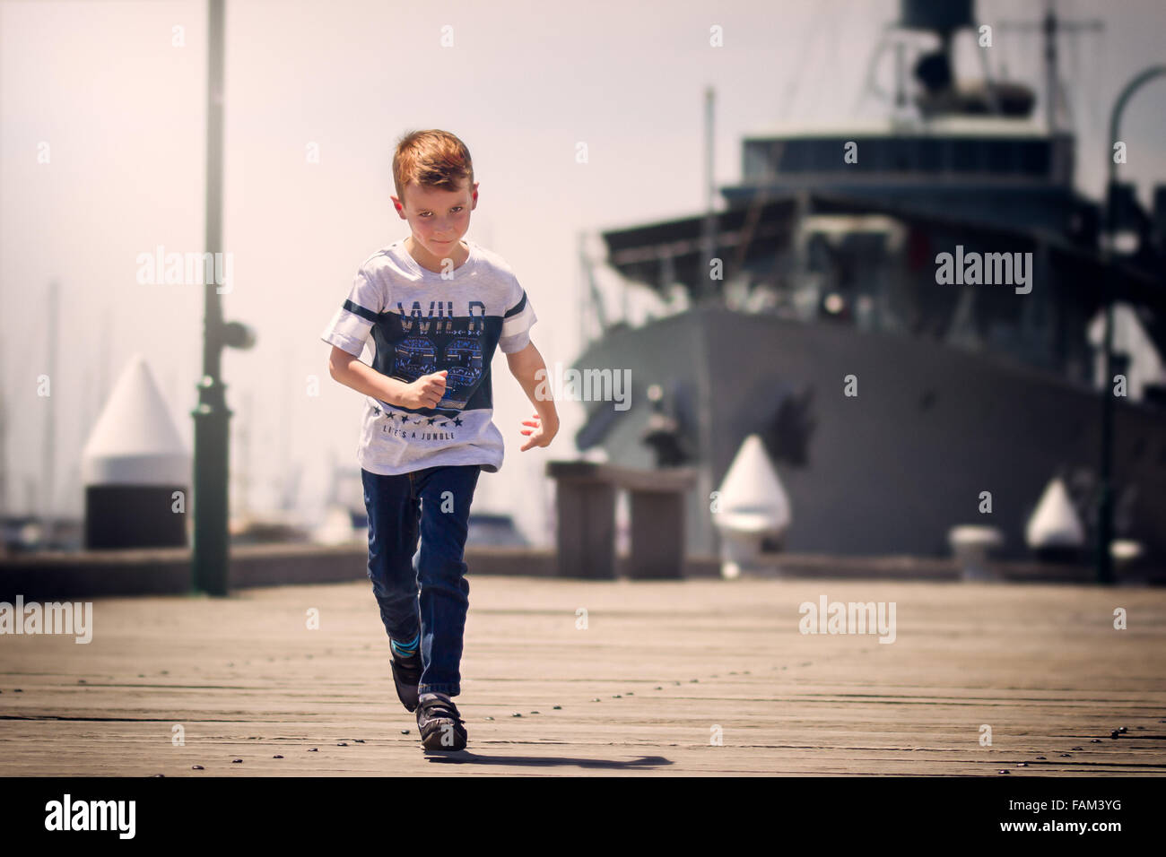 Boy running with warship in background Stock Photo - Alamy