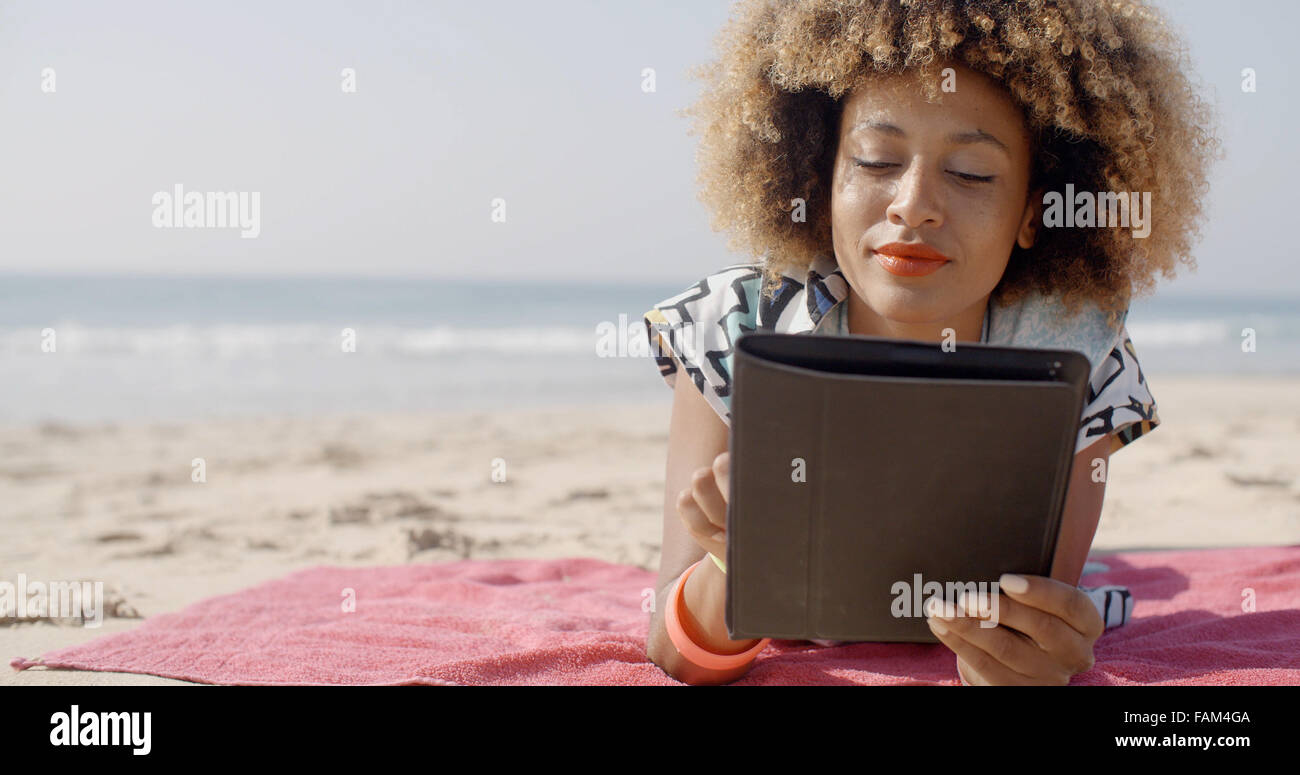 Woman Uses A Tablet On The Beach Stock Photo - Alamy