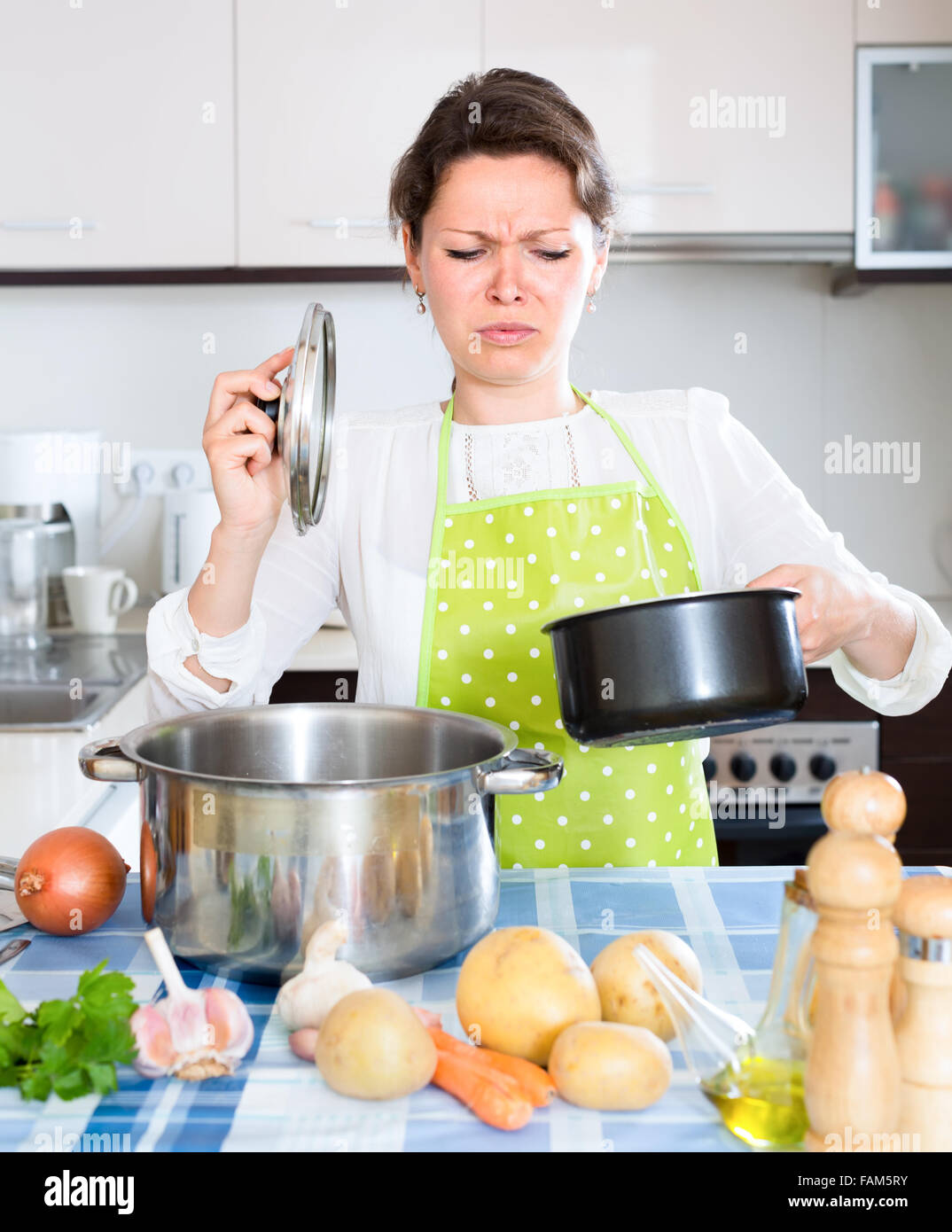 Young woman in kitchen opened a pan with smelly foul food inside Stock ...