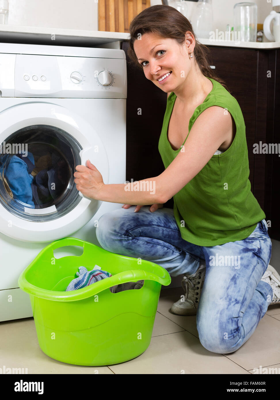 Home laundry. Attractive smiling girl using washing machine at home ...