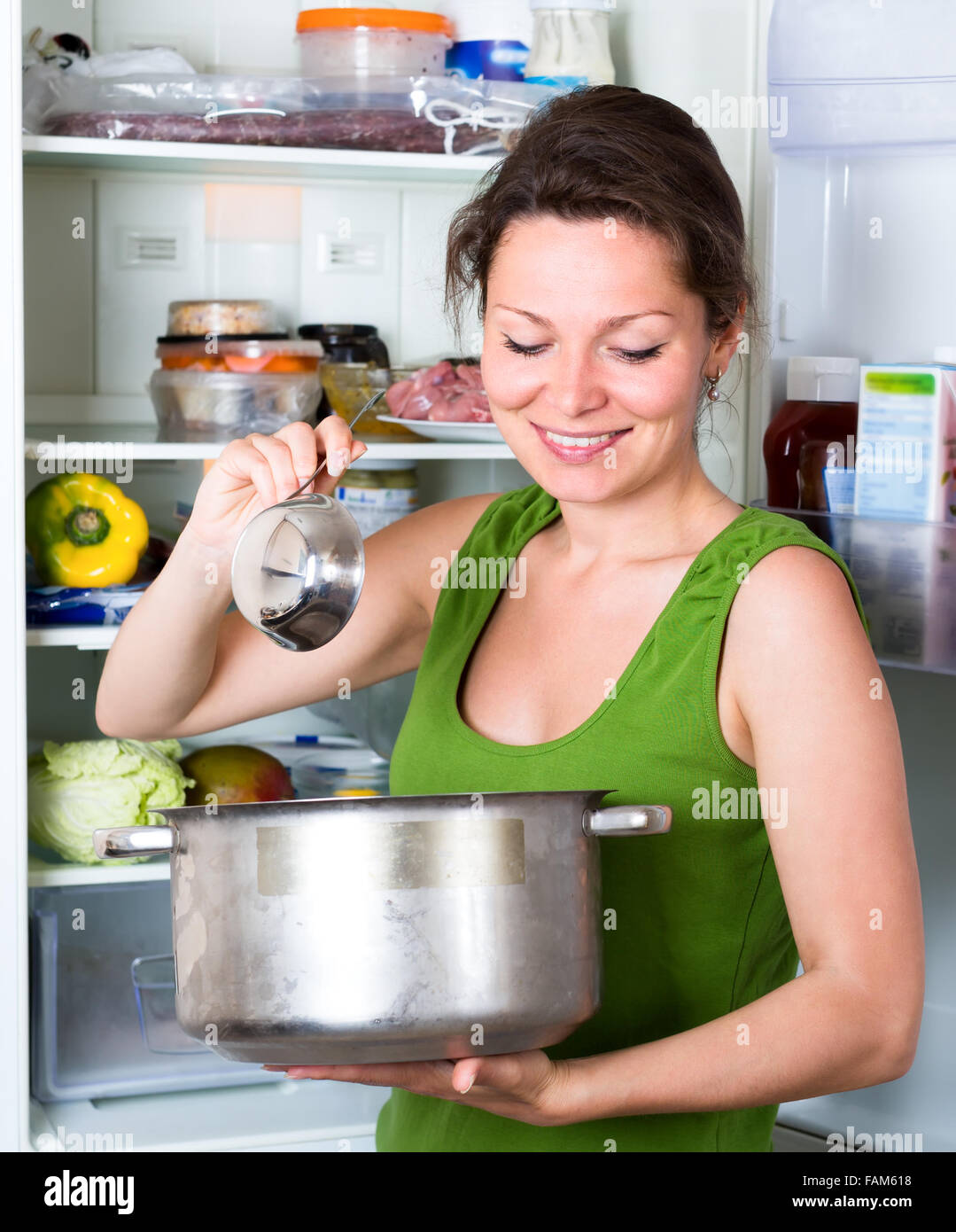 Hungry woman eating from a pan near open fridge in kitchen Stock Photo ...