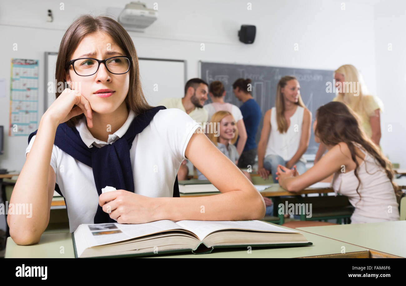 Alone student being bullied by a group of students her chin on her hand ...