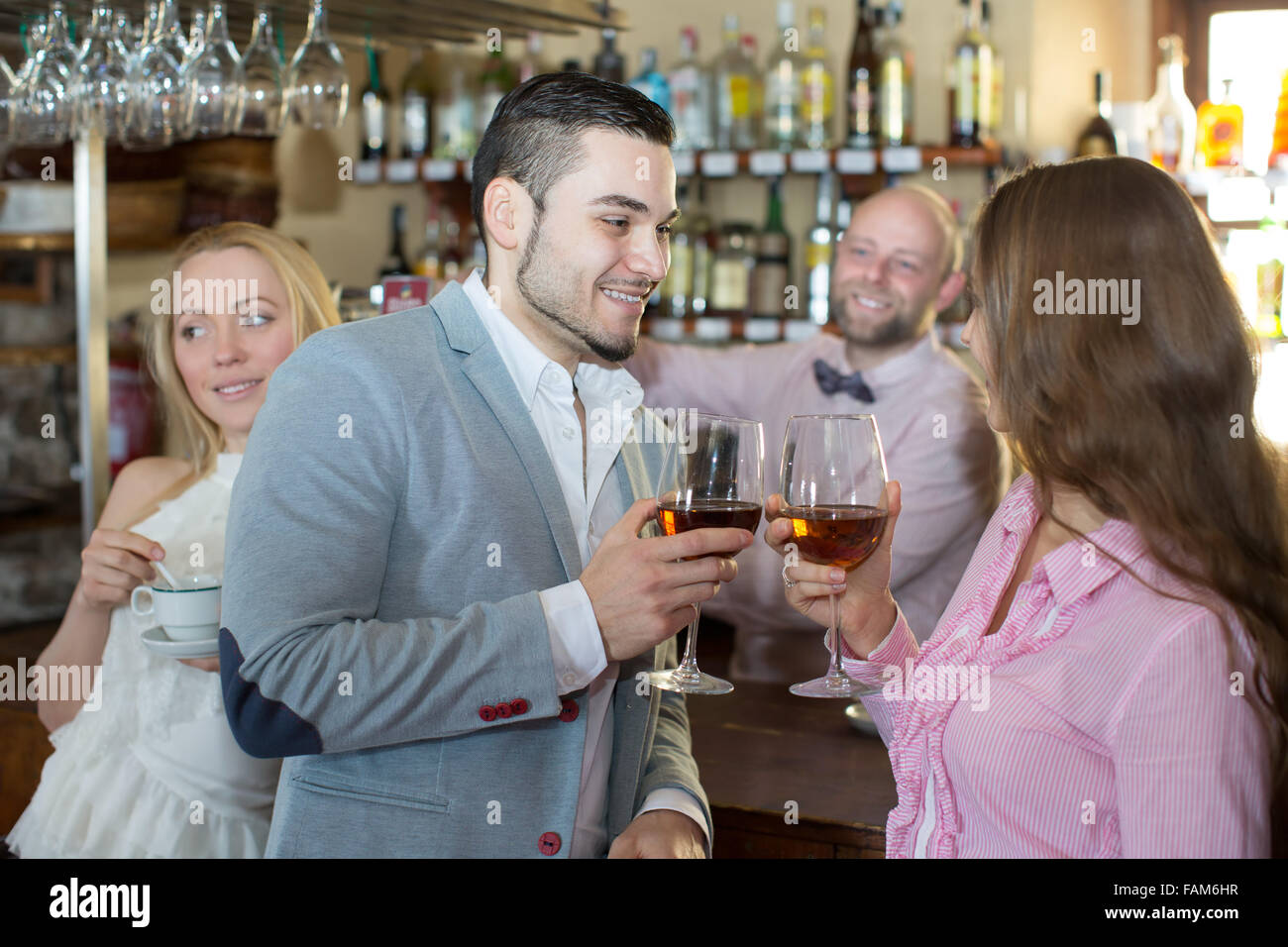 Positive bartender entertaining guests at bar counter in bar Stock ...
