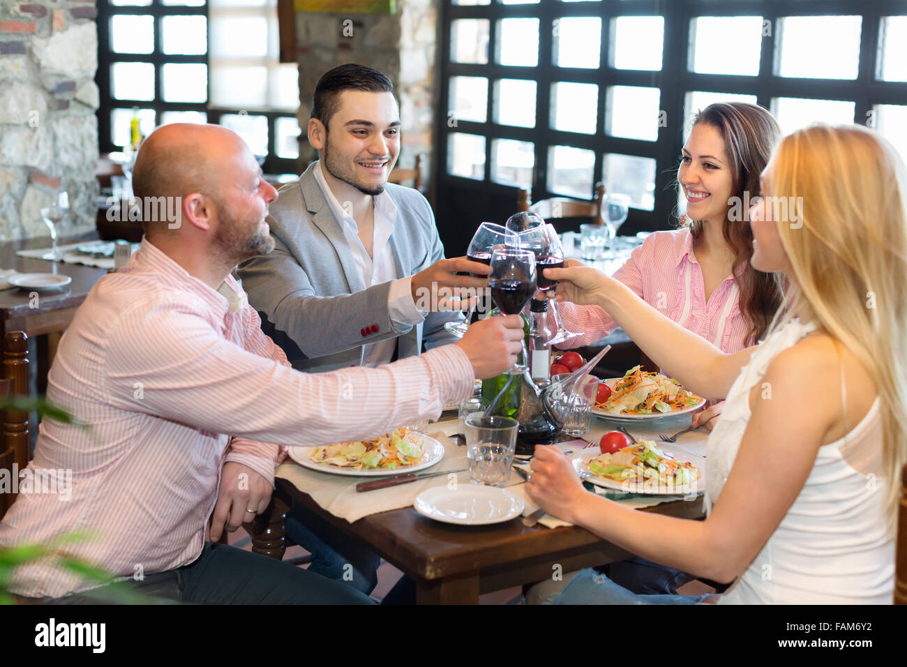 Four happy people sitting at restaurant table Stock Photo - Alamy