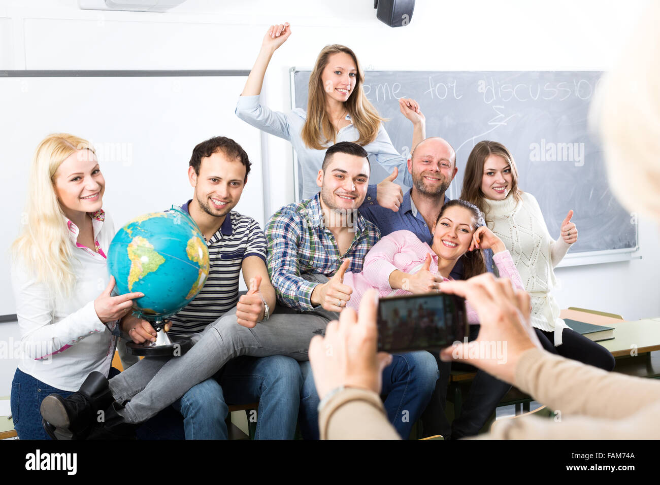 Female mature professor taking a photograph of her graduates in a ...