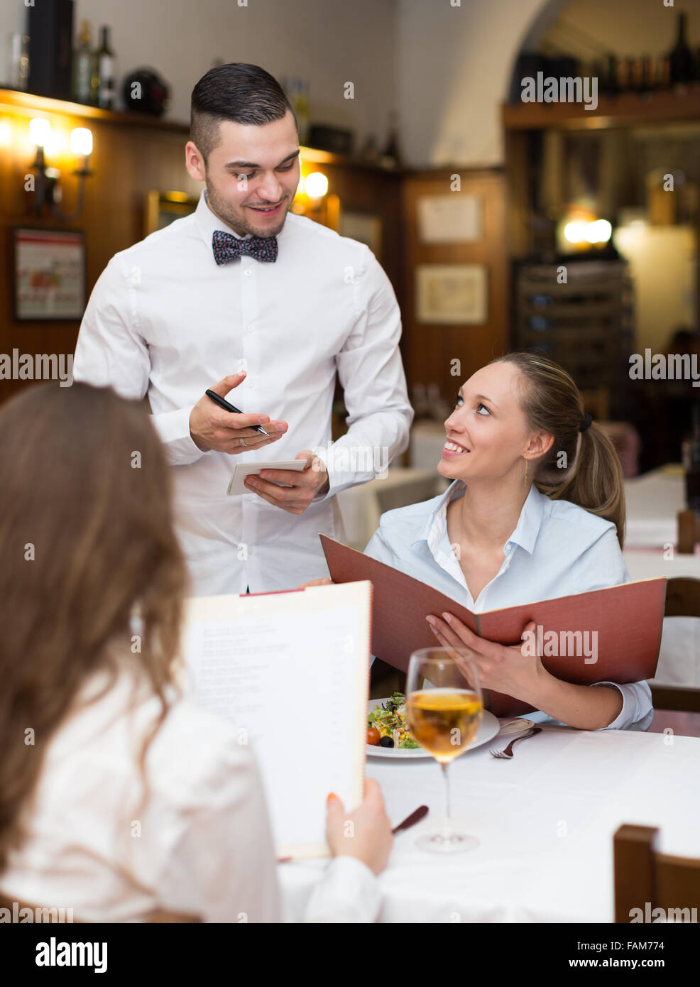 Smiling waiter serving bar guests with beverages Stock Photo - Alamy