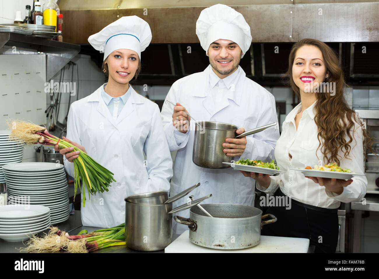 Team of two chefs and female waiter at restaurant kitchen. Selective ...