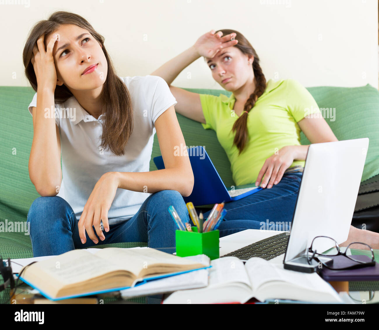 Dreary teenage student girls study at home with a books and computers ...