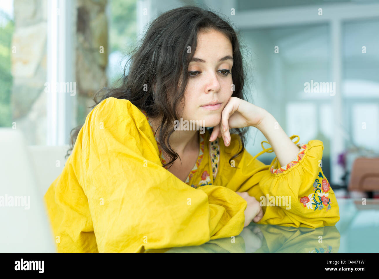 Sad woman sitting along at the table indoor Stock Photo - Alamy