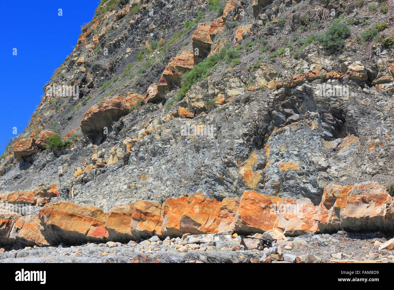 Steep slopes with sparse vegetation and visible layers of rock Stock ...