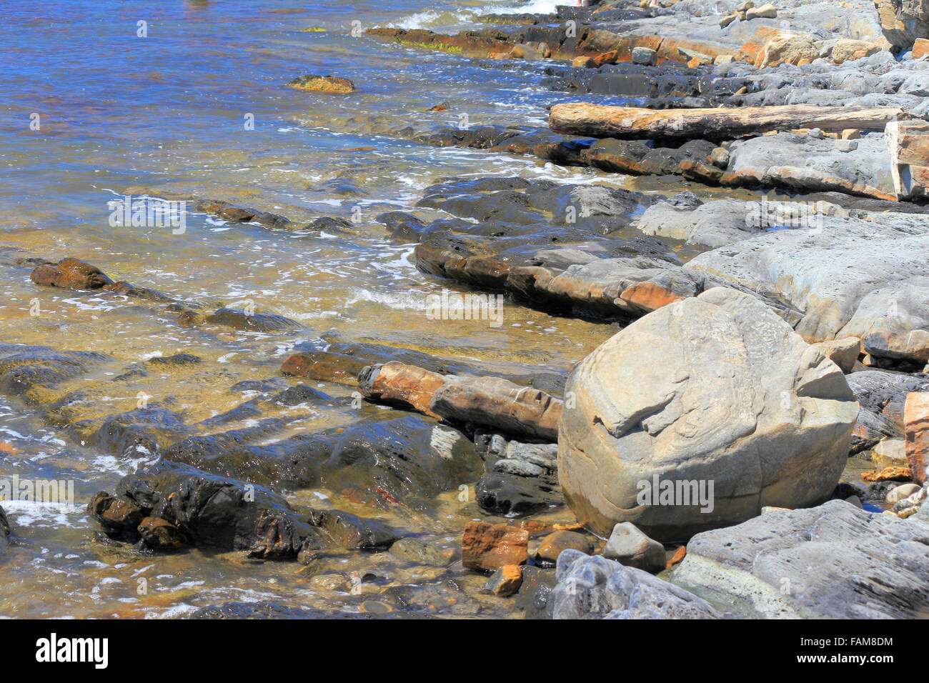 The layers of rocks partially submerged under sea waters Stock Photo ...