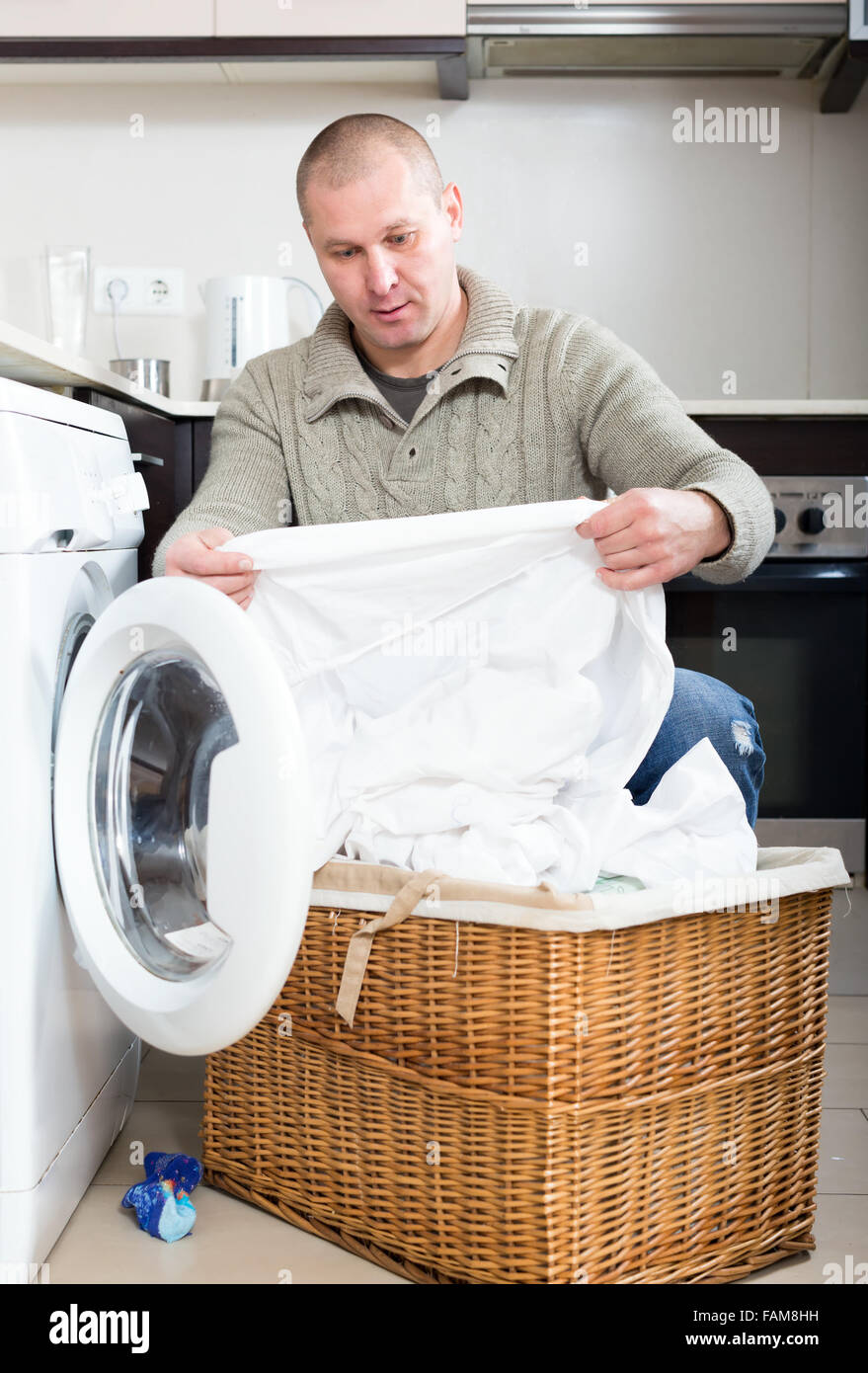 Sad guy doing laundry with washing machine at home Stock Photo - Alamy