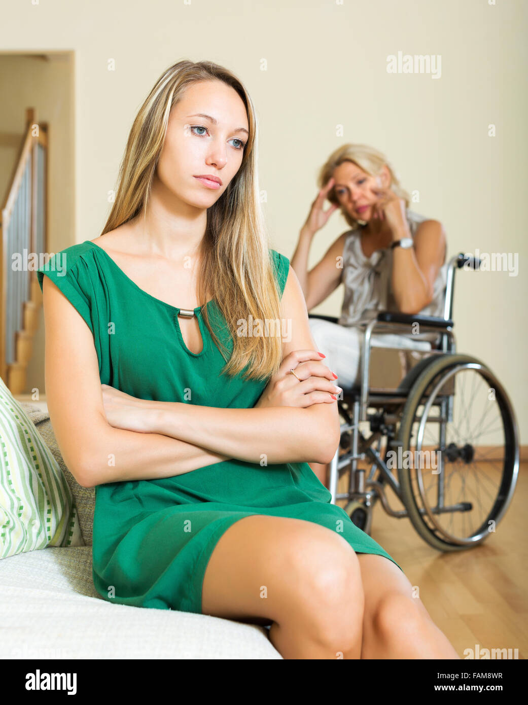 Tired woman and depressed disabled person on chair indoor Stock Photo ...