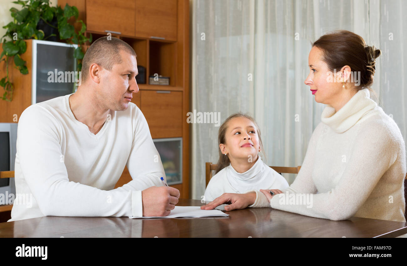 Sad family with little daughter reading financial documents at the ...