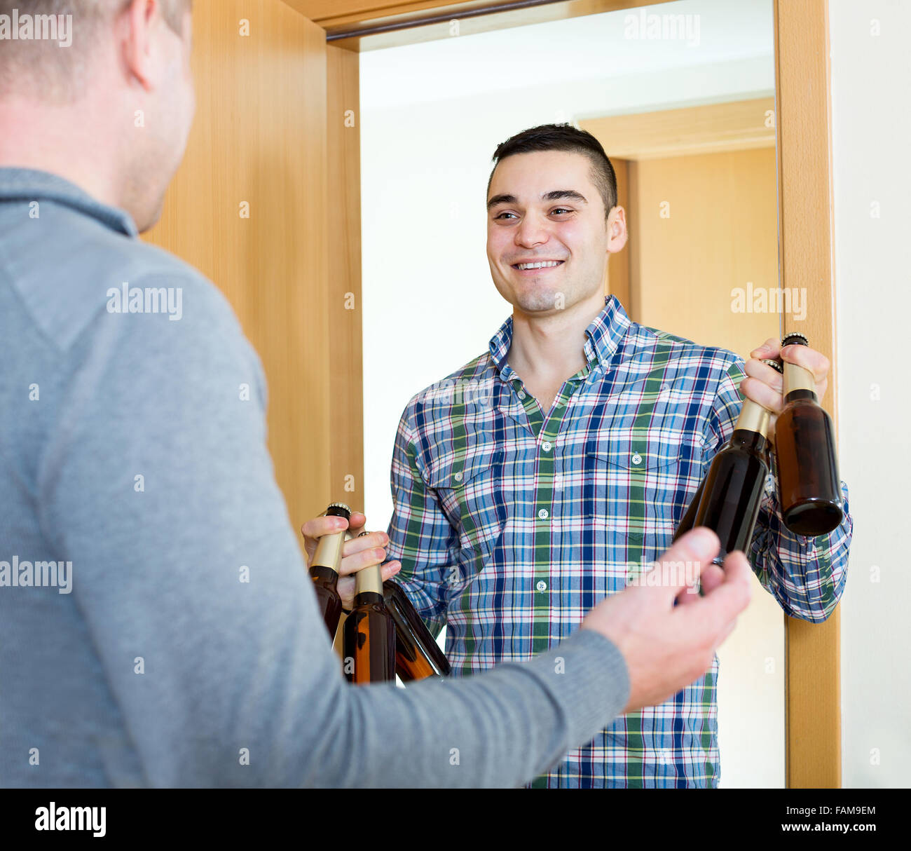 Happy adult man visiting friend and bringing beer Stock Photo - Alamy