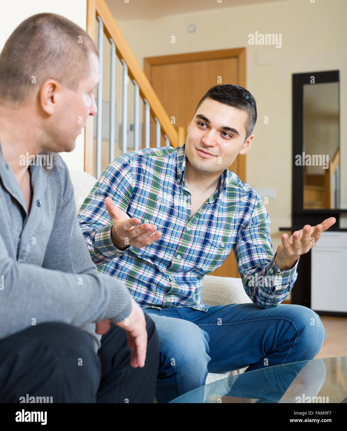 Positive conversation between two adult smiling men indoors Stock Photo ...