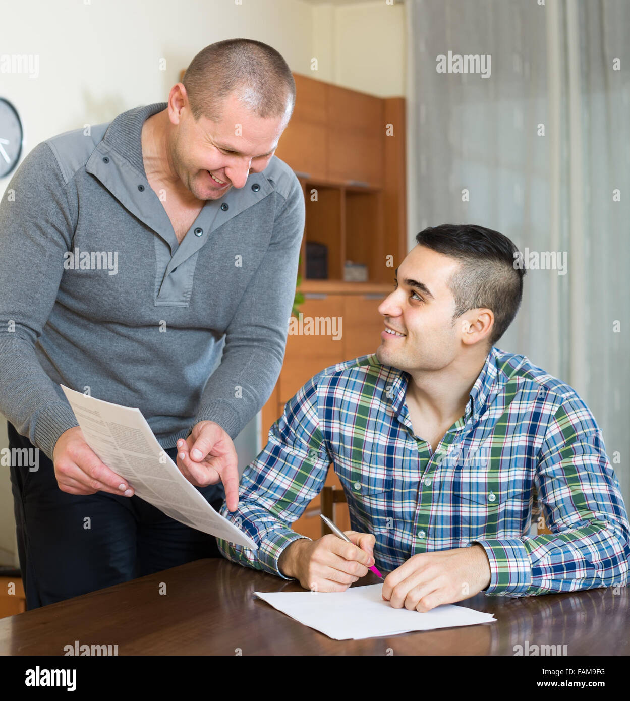 Smiling male agent explaining to client terms of contract at home Stock ...