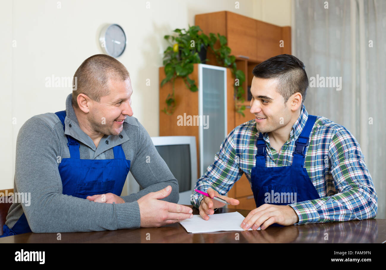 Two smiling men in uniform reading contents of order at office Stock ...