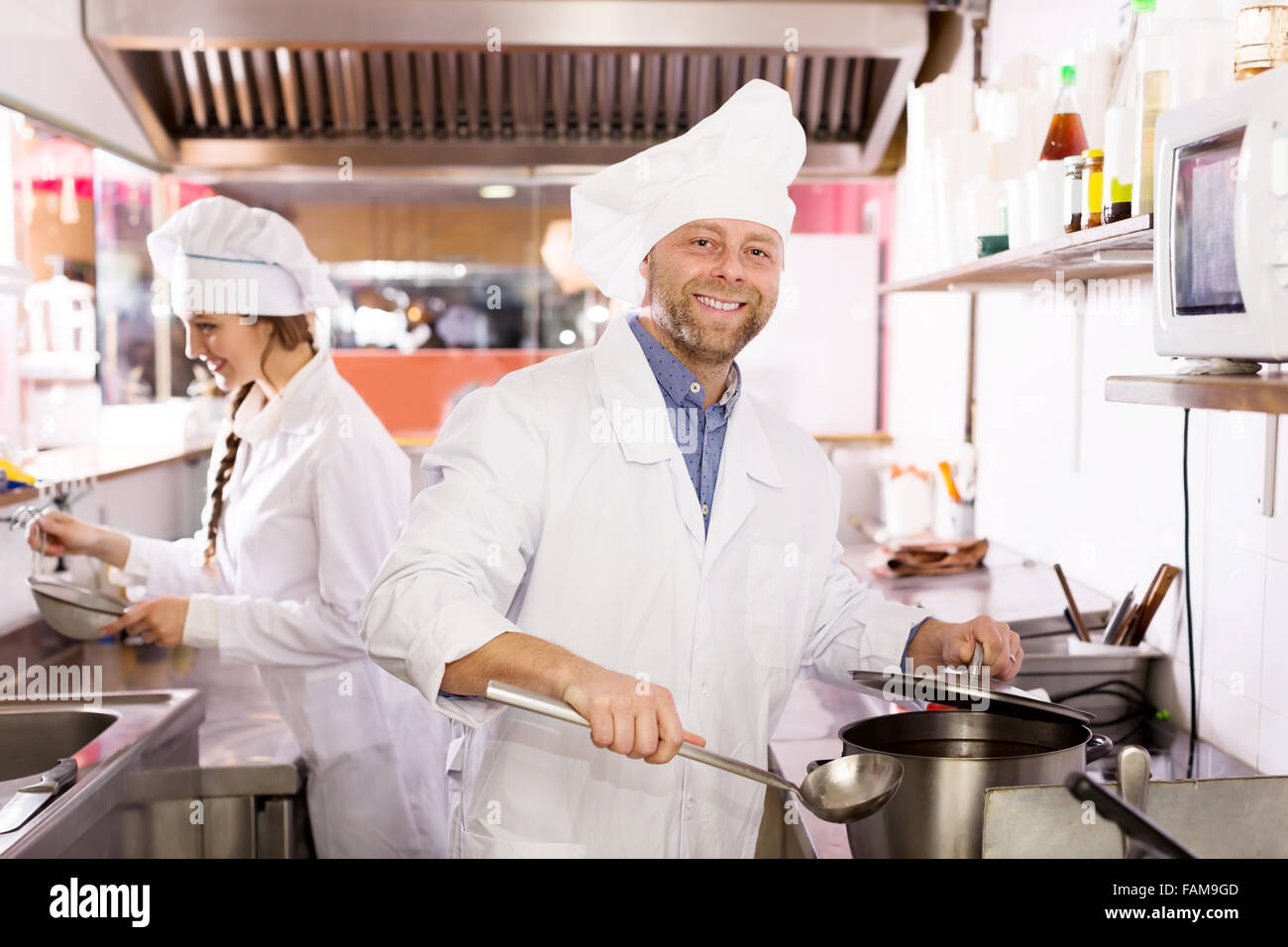 Cheerful cooks cooking at professional kitchen in the take-away ...