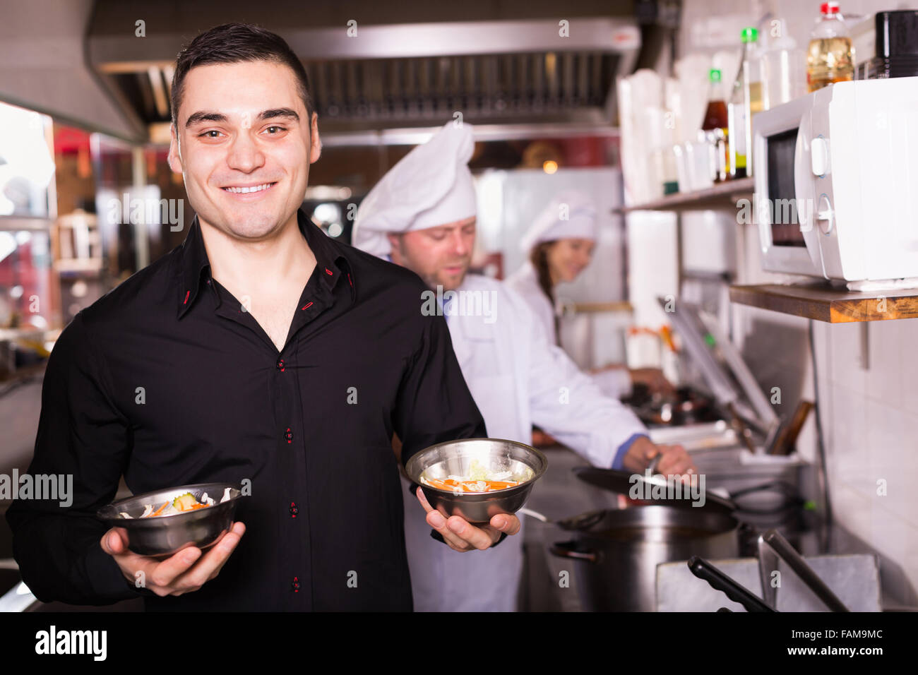Chefs and handsome waiter working at eating house Stock Photo - Alamy