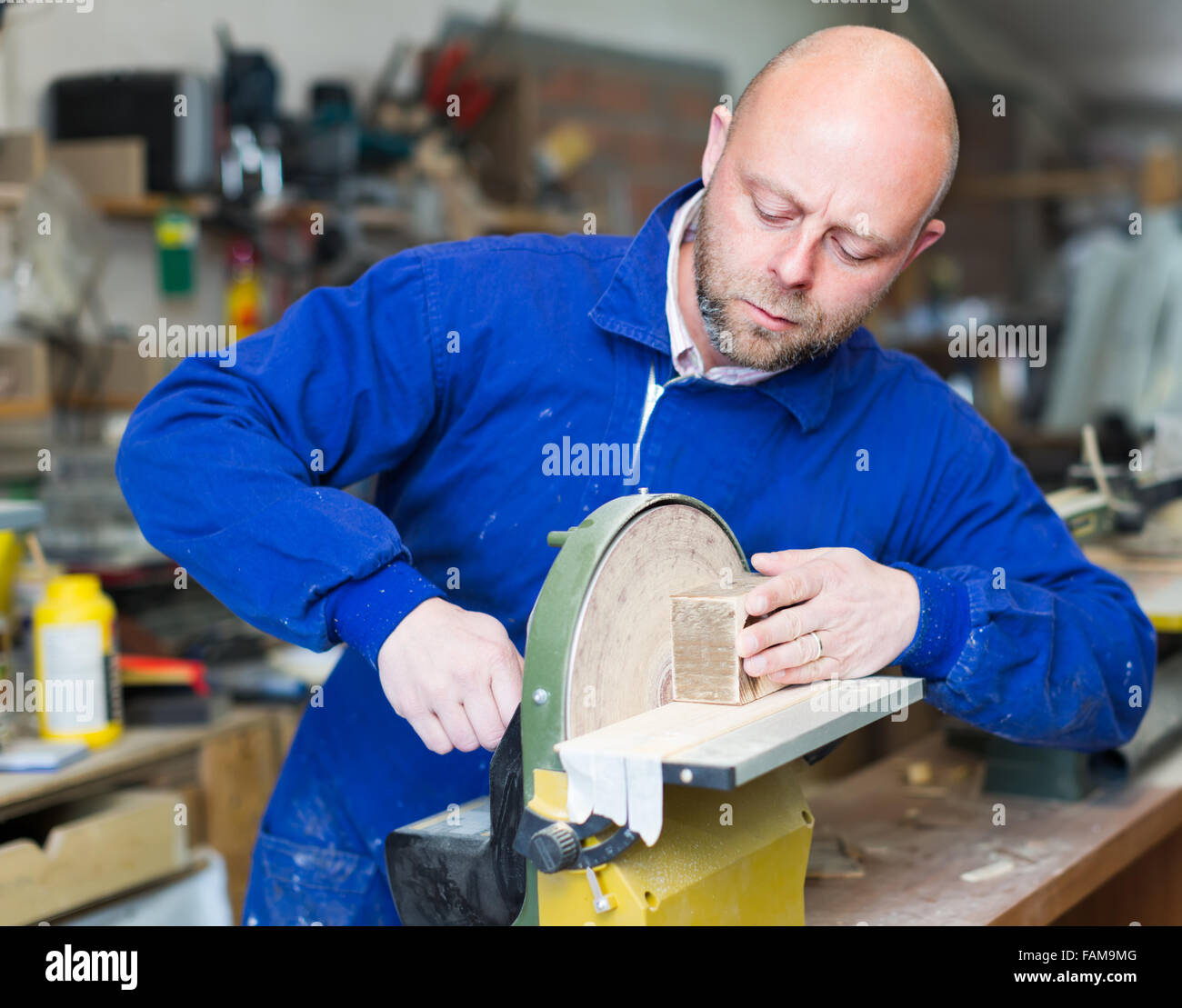 Portrait of serious woodworker working on a machine at wood workshop ...