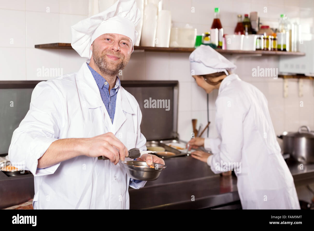 smiling adult man and young girl cooks cooking at professional kitchen ...