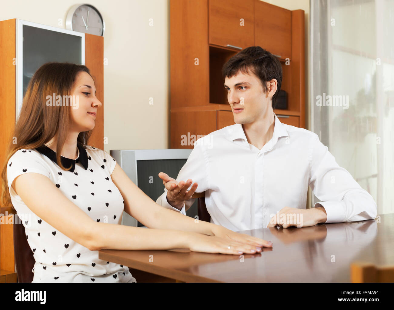 Casual young couple having serious talking at table in room Stock Photo ...